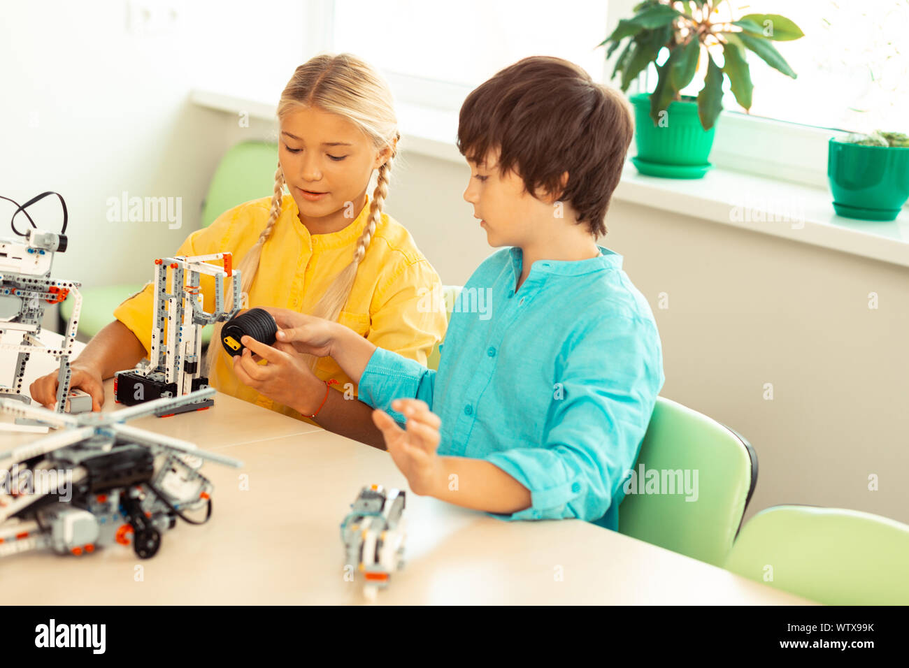 Boy helping his classmate with her project Stock Photo - Alamy