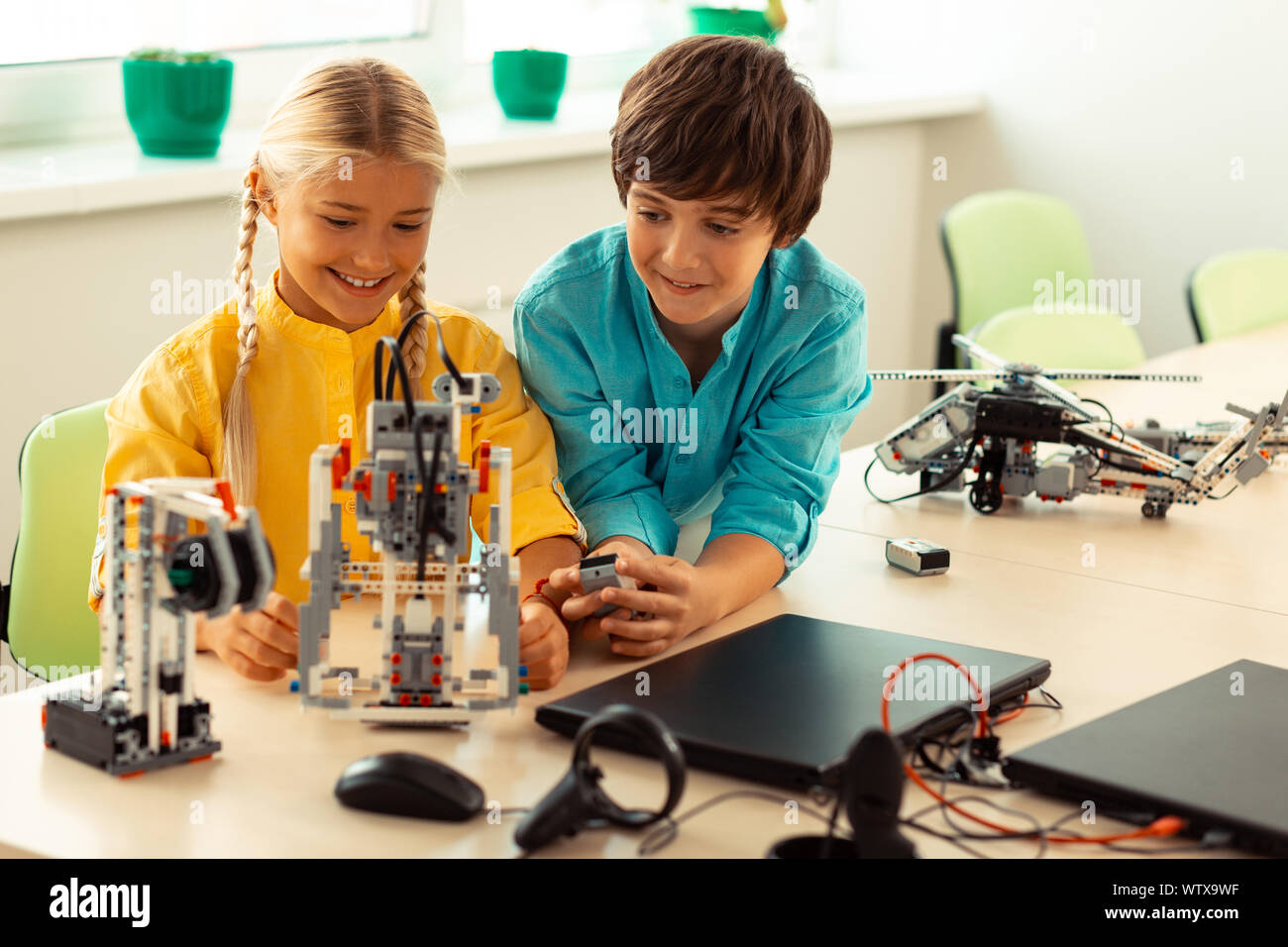 Boy helping his classmate turning on a robot Stock Photo - Alamy