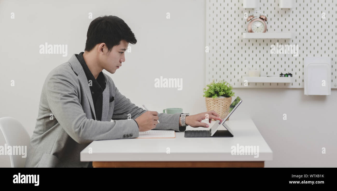 Young start up man working on his project with tablet and writing on ...