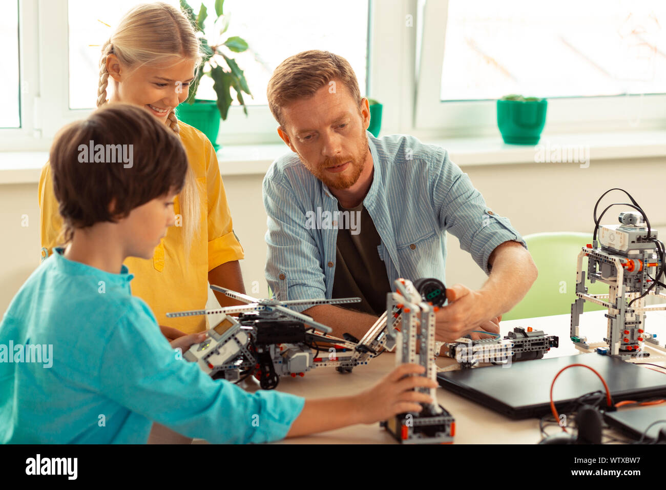 Teacher helping pupils building with construction set Stock Photo - Alamy