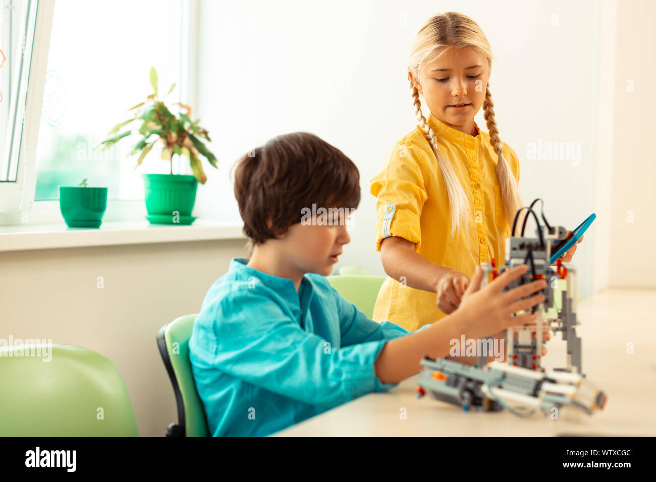 Girl helping her classmate constructing a robot Stock Photo - Alamy