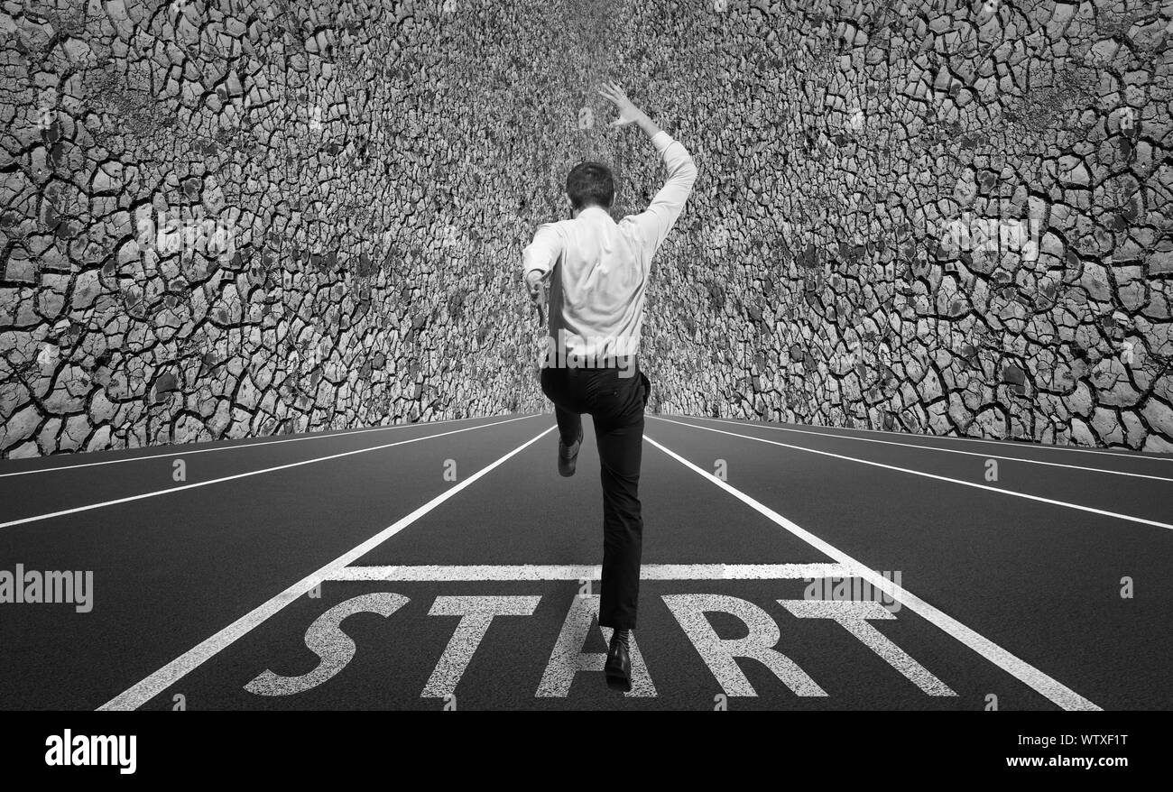 Businessman jumping on a starting grid with the wall on the background ...