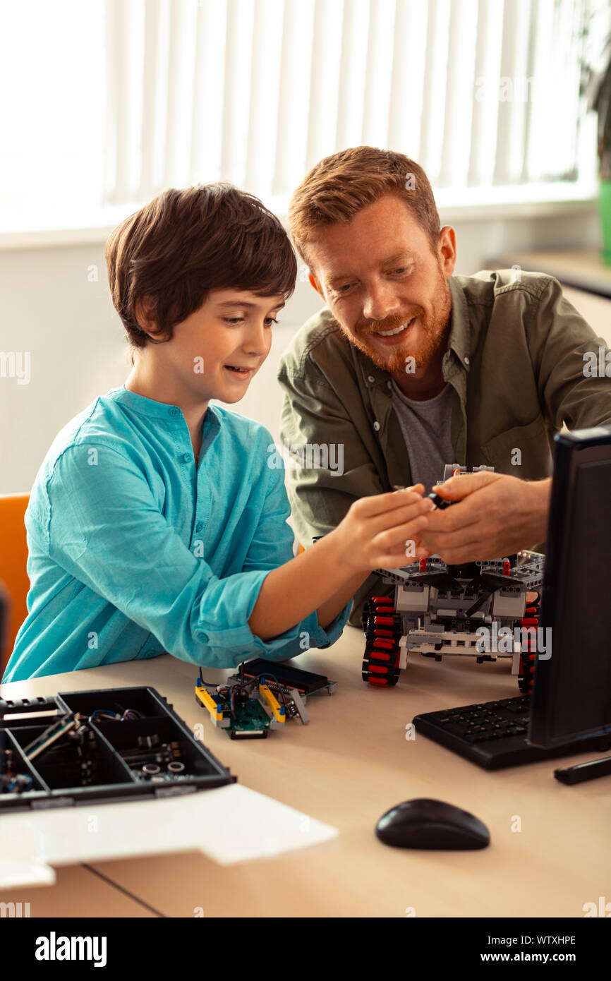 Science teacher helping his pupil with robot building Stock Photo - Alamy