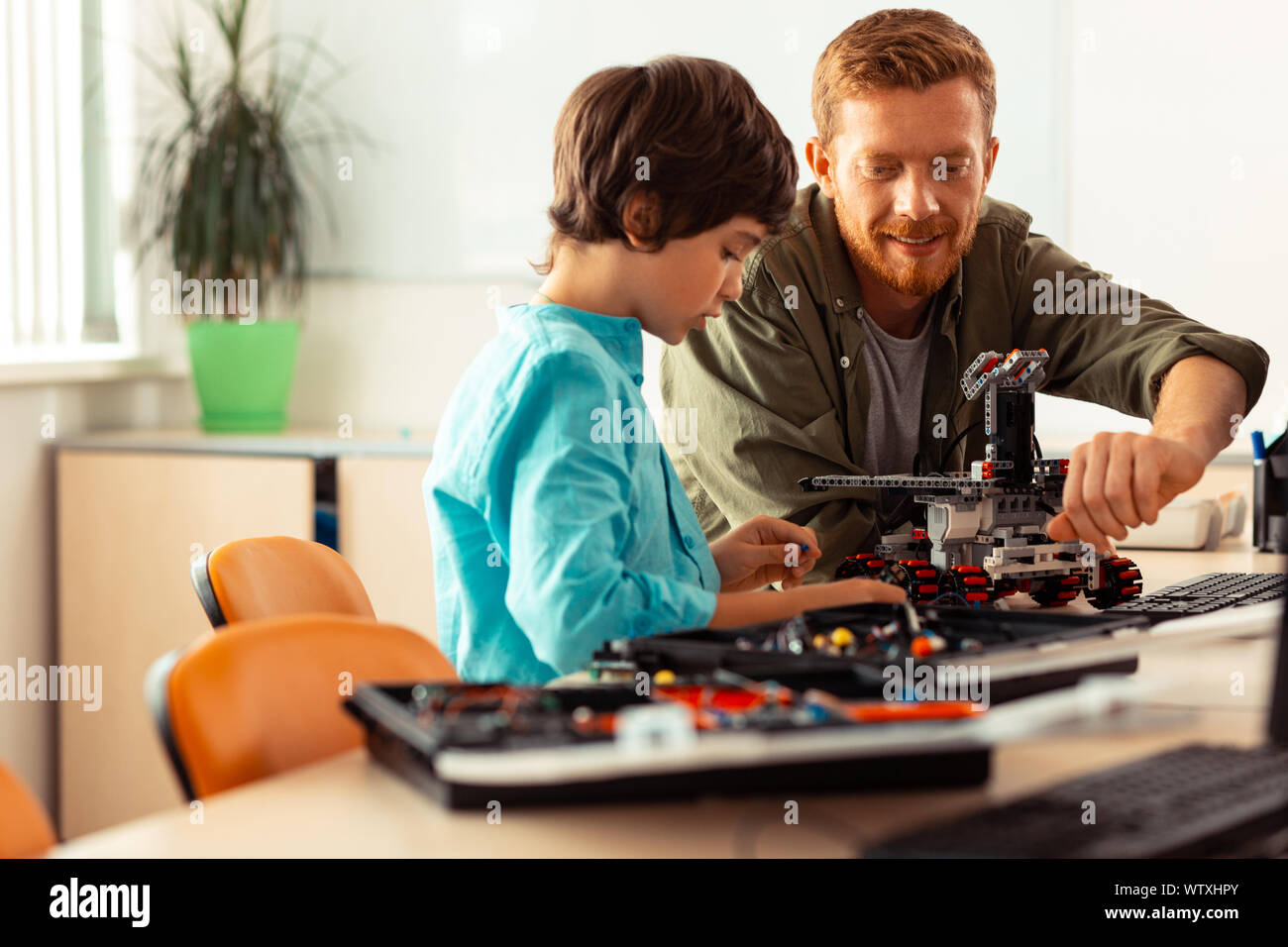 Teacher helping a schoolboy building his robot Stock Photo - Alamy