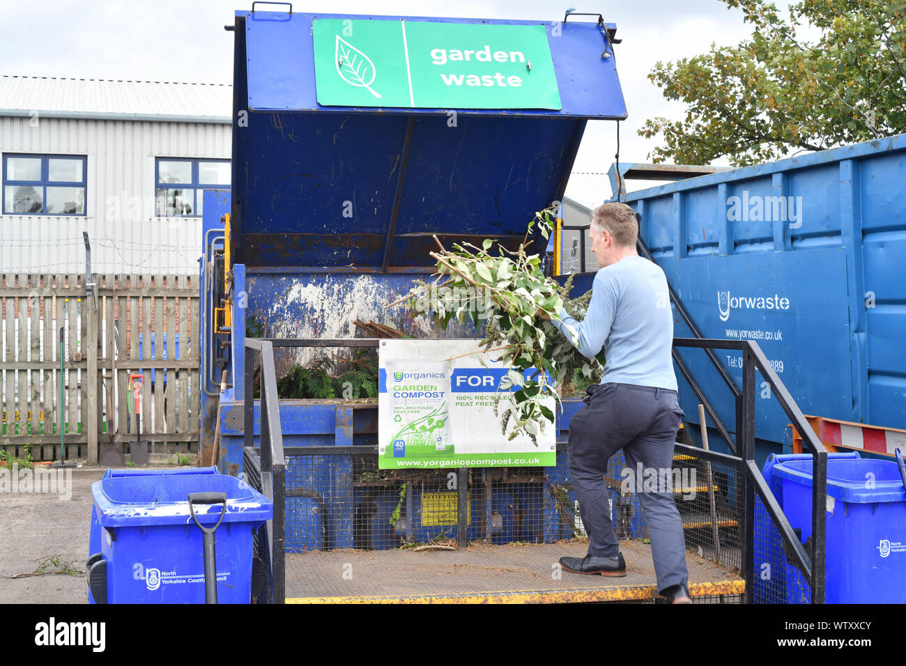 man carrying garden cuttings for recycling into compost at household ...