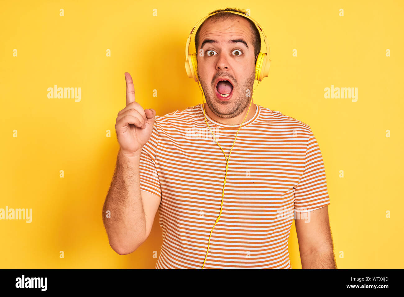 Young man listening to music using headphones standing over isolated ...
