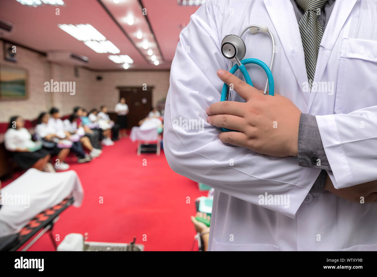 Doctor in gown uniform with stethoscope standing and fold his arms over ...