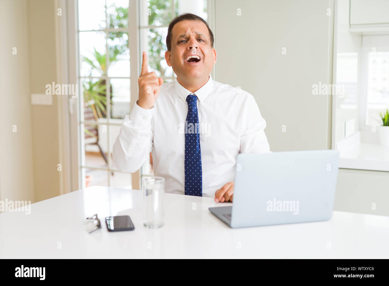 Middle age business man working with computer laptop pointing finger up ...