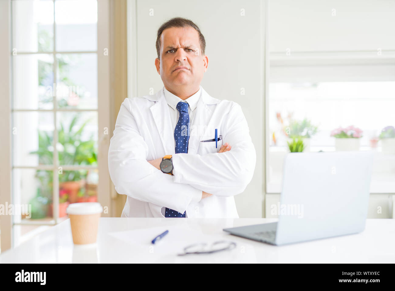 Middle age doctor man wearing white medical coat working with laptop at ...