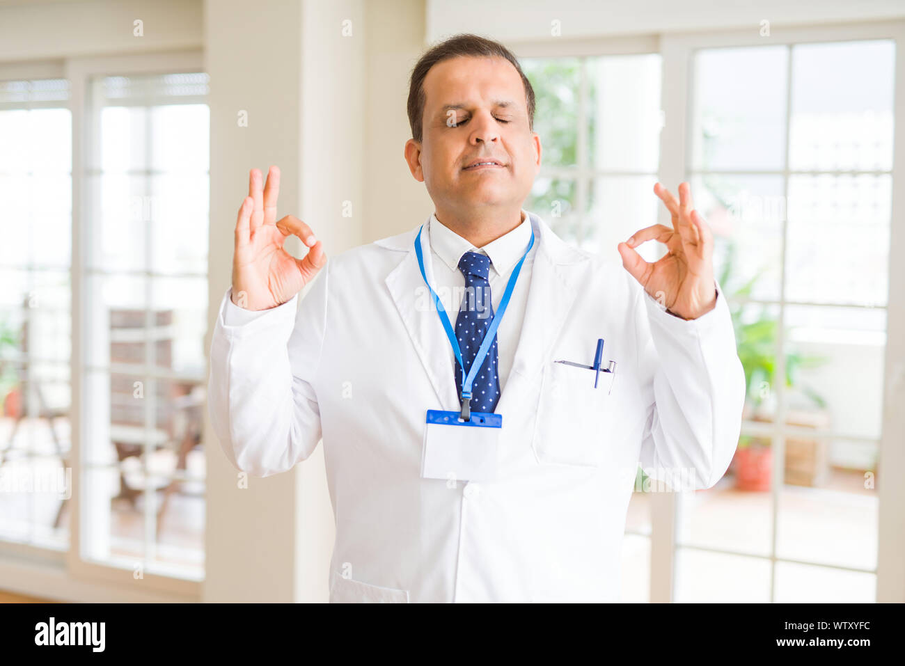 Middle age doctor man wearing medical coat and id card badge over white ...