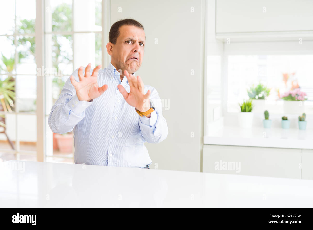 Middle age man sitting at home afraid and terrified with fear ...