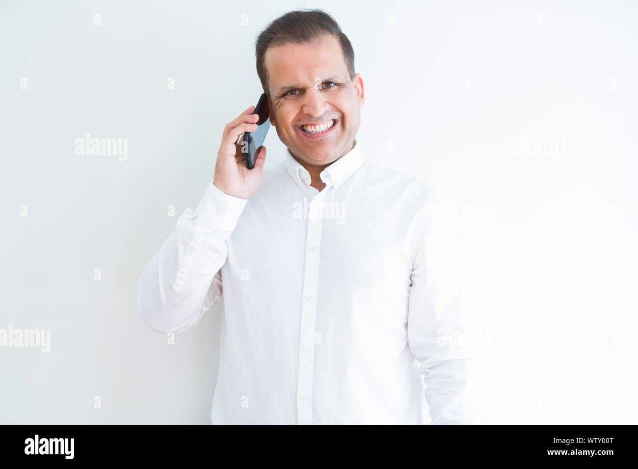 Middle age man calling using smartphone with a happy face standing and ...