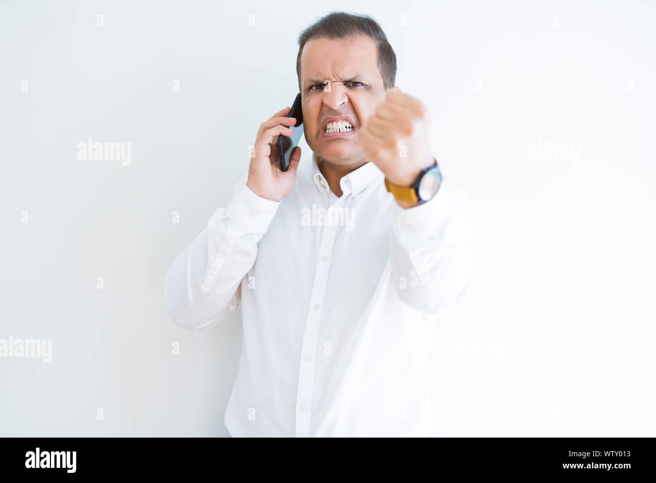 Middle age man calling using smartphone annoyed and frustrated shouting ...