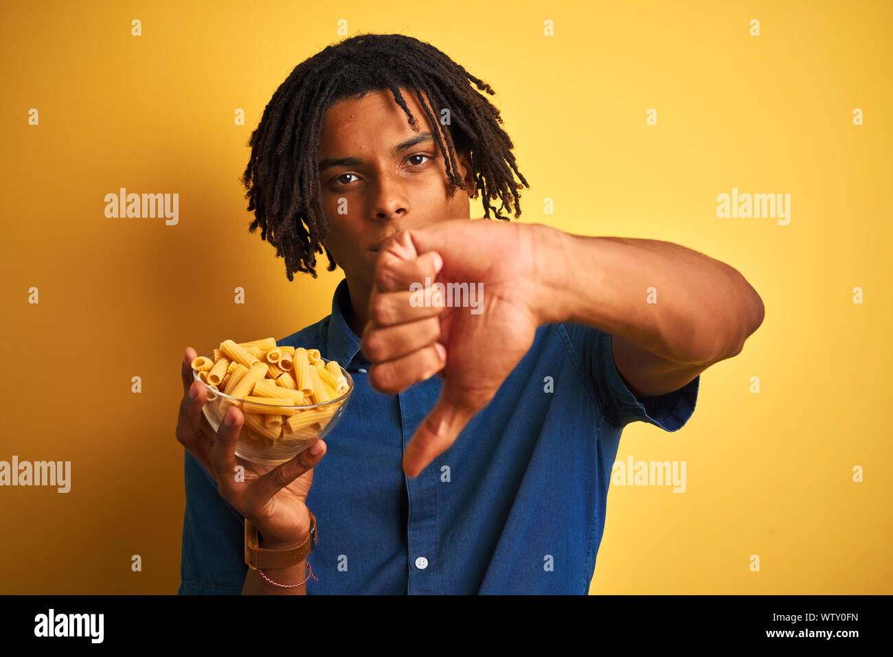 Afro american man with dreadlocks holding pasta macaroni over isolated ...