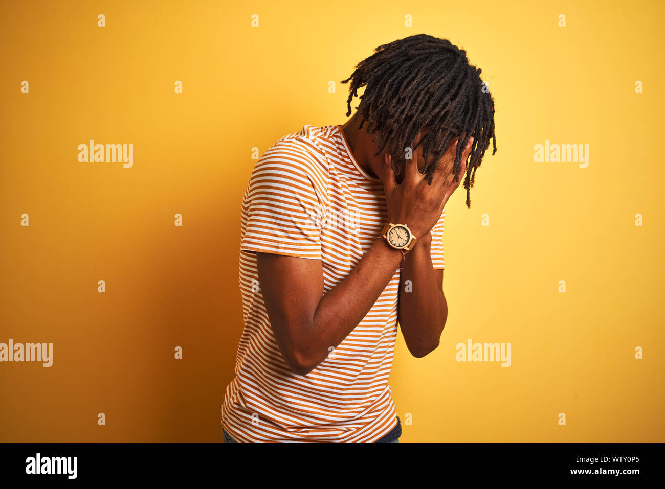 Afro man with dreadlocks wearing striped t-shirt standing over isolated ...