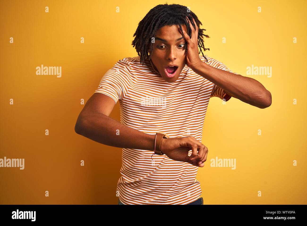 Afro man with dreadlocks wearing striped t-shirt standing over isolated ...