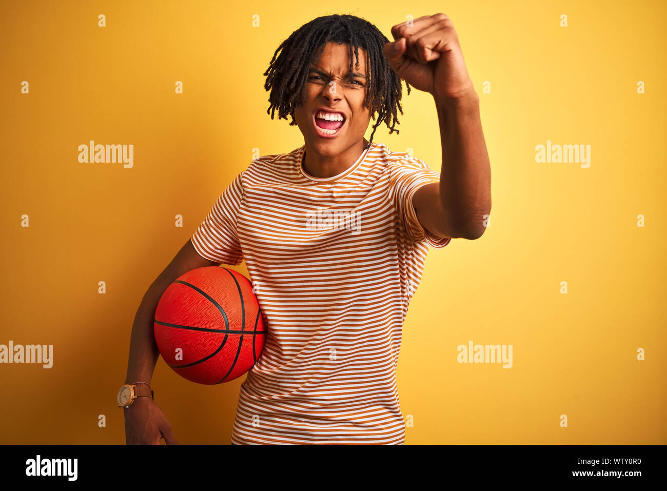 Afro sportsman with dreadlocks holding basketball ball over isolated ...