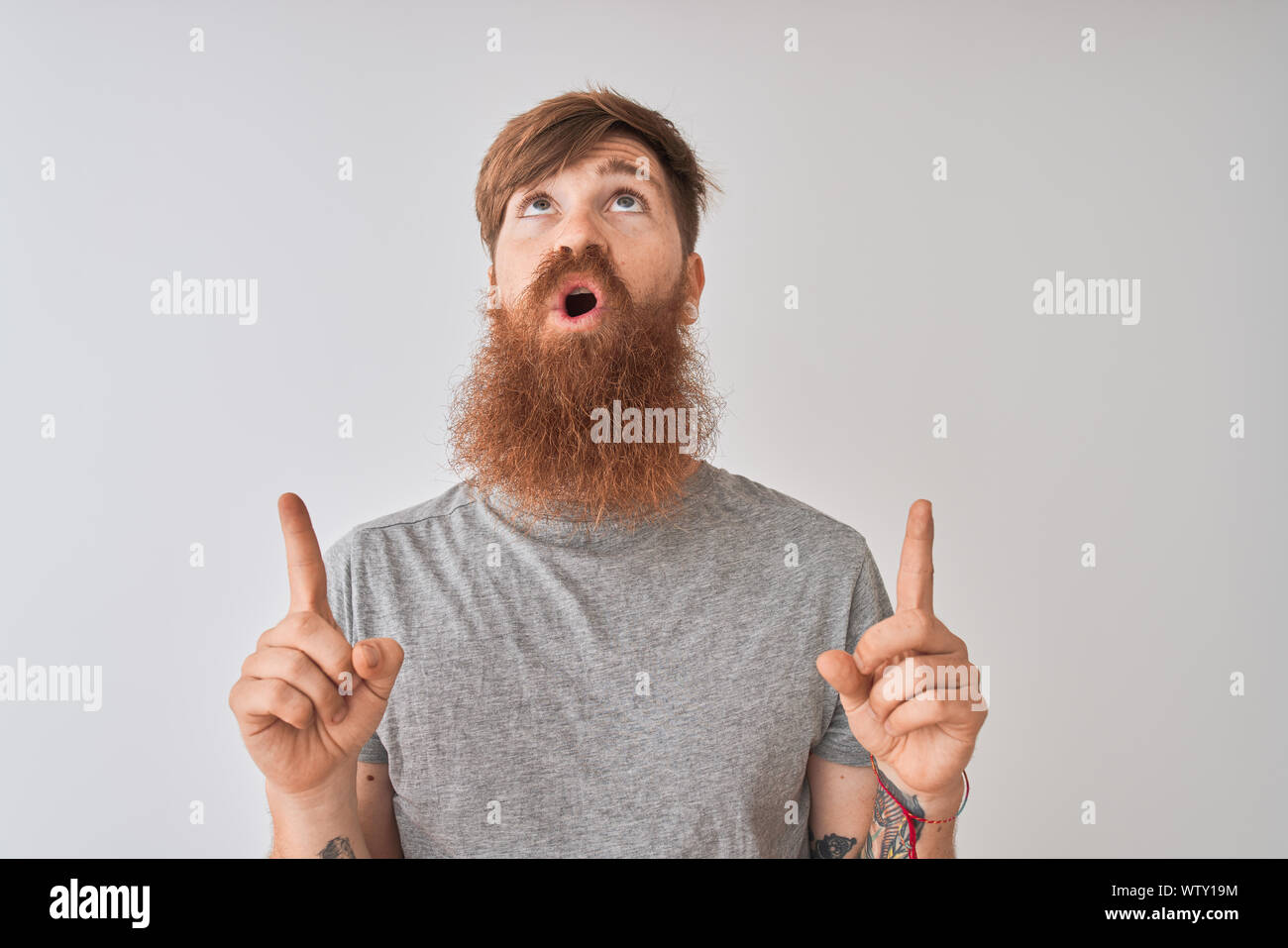 Young redhead irish man wearing t-shirt standing over isolated grey ...