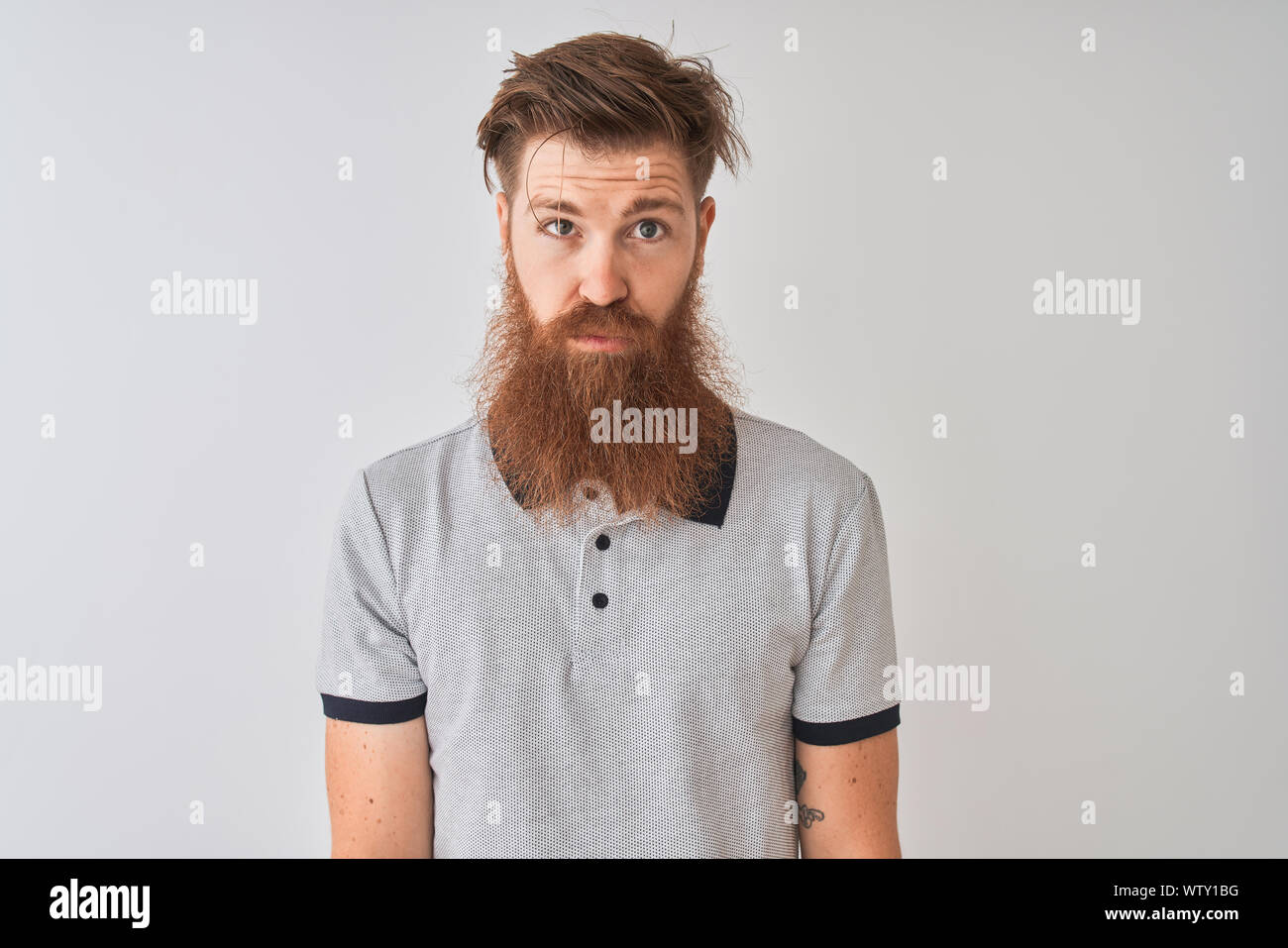 Young redhead irish man wearing grey polo standing over isolated white ...