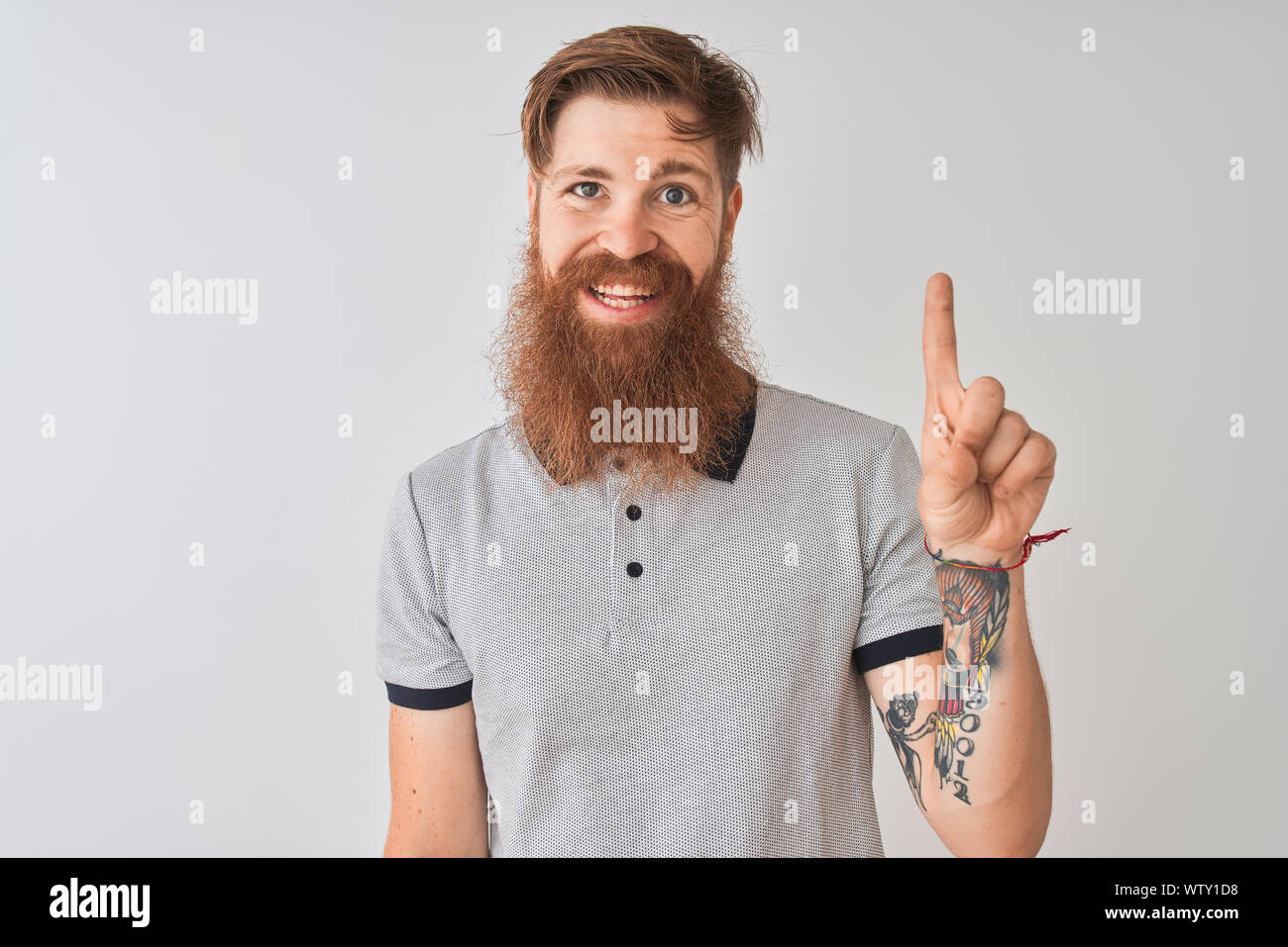 Young redhead irish man wearing grey polo standing over isolated white ...