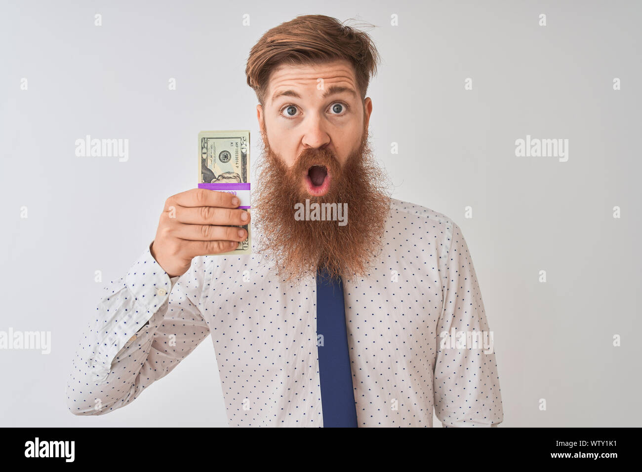 Young redhead irish businessman holding dollars standing over isolated ...