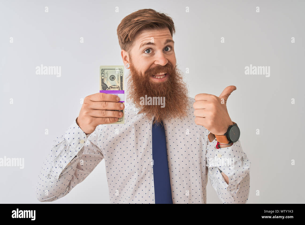 Young redhead irish businessman holding dollars standing over isolated ...