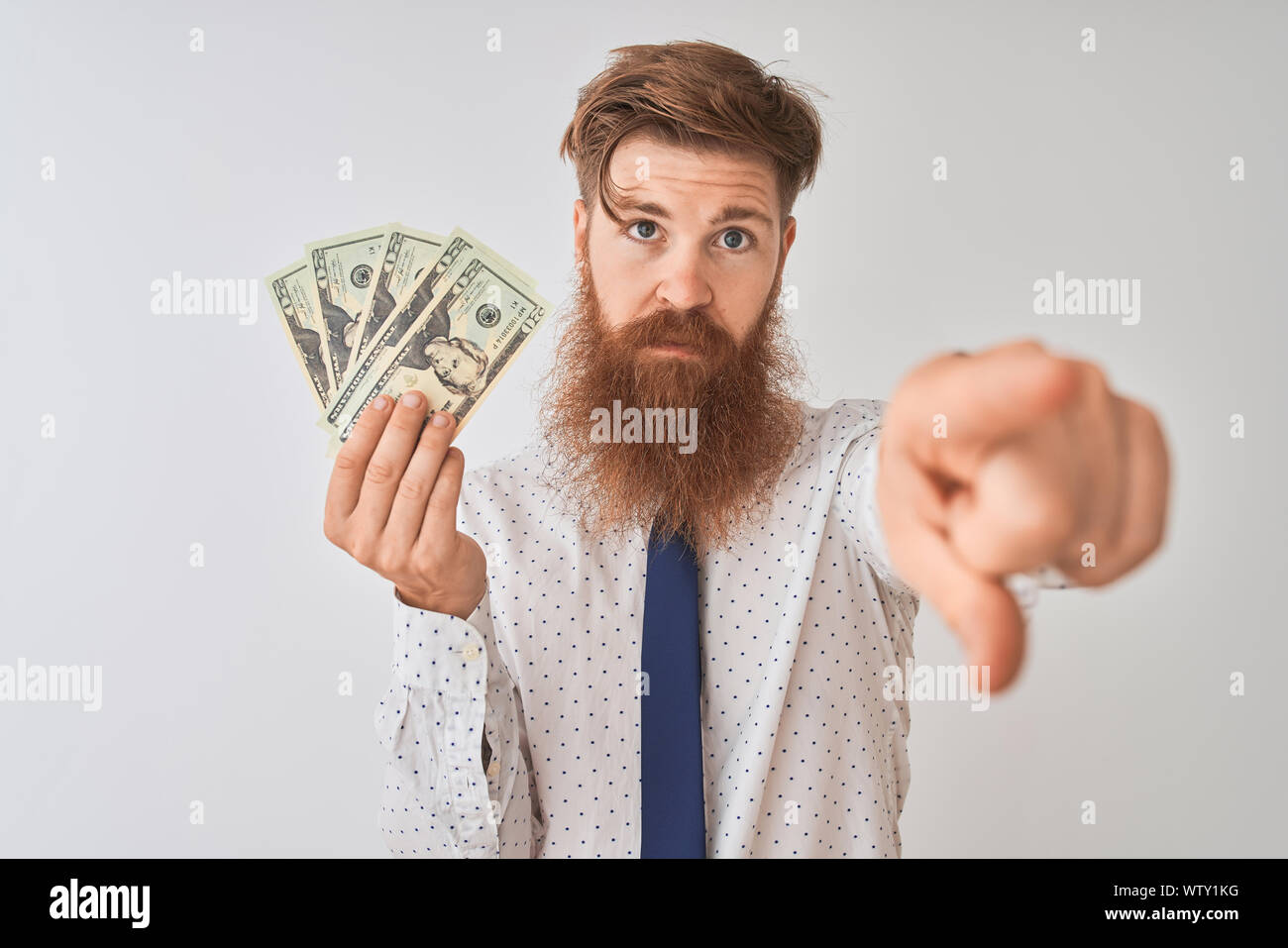 Young redhead irish businessman holding dollars standing over isolated ...