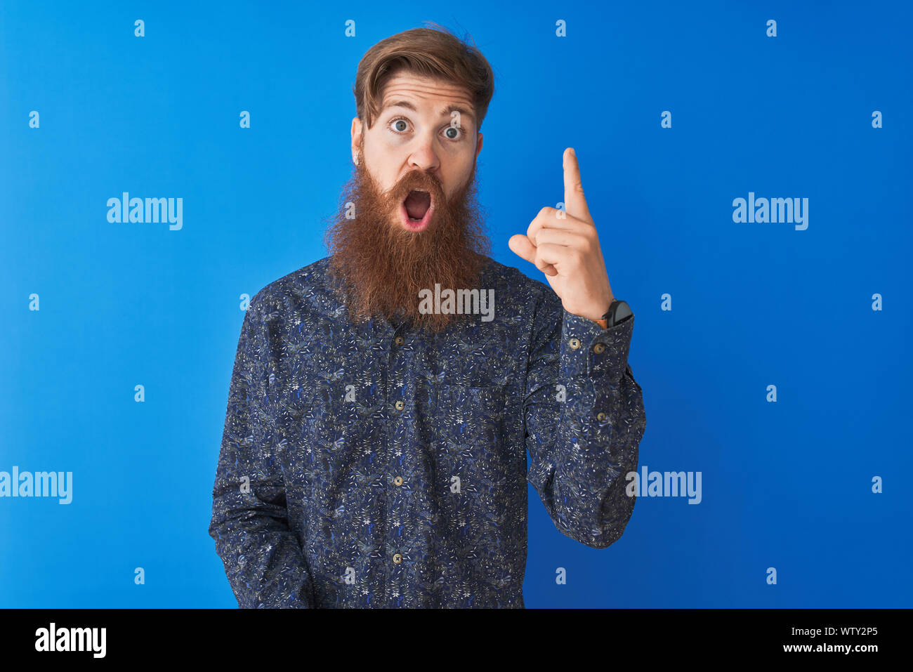 Young redhead irish man wearing floral summer shirt standing over ...