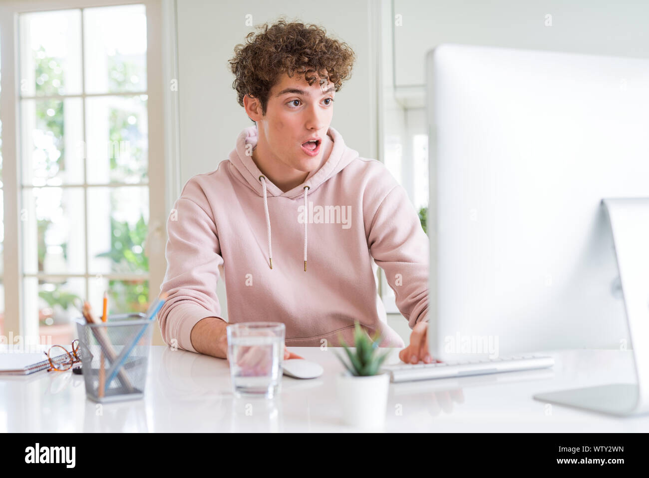 Young student man using computer scared in shock with a surprise face ...