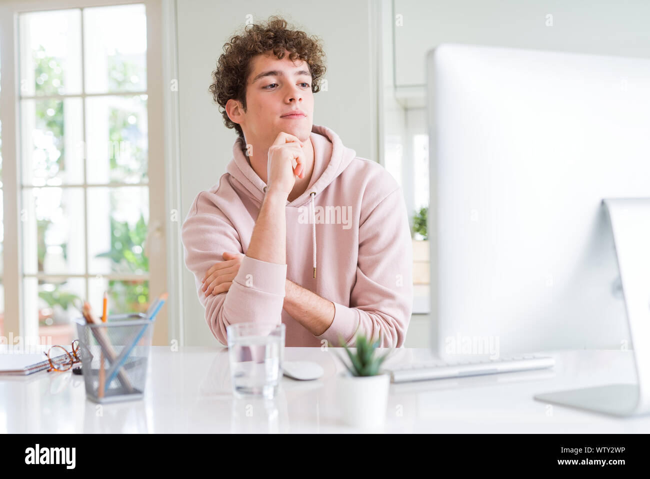 Young student man using computer serious face thinking about question ...