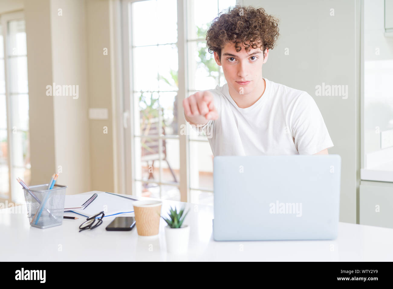 Young student man working and studying using computer laptop pointing ...