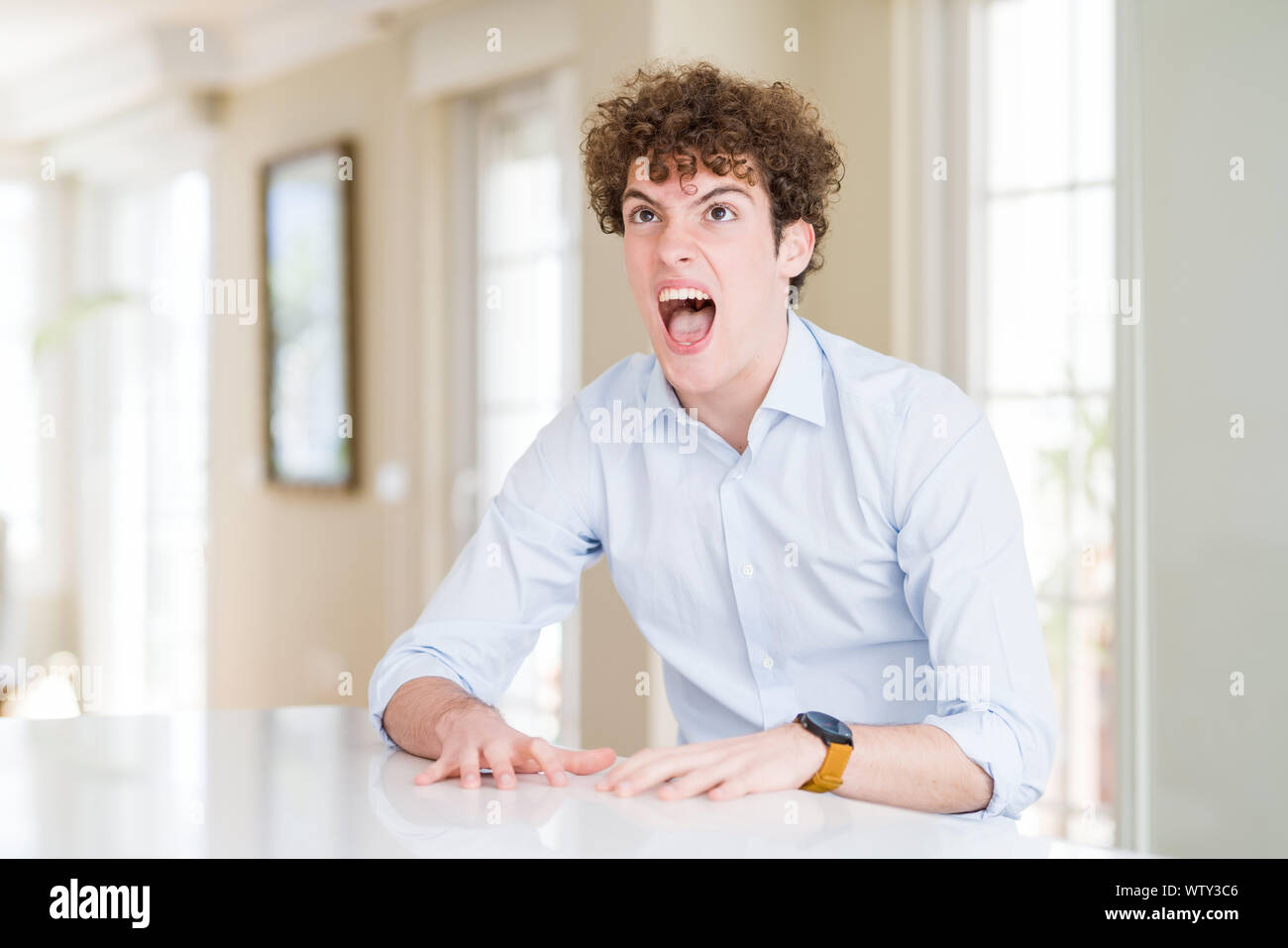Young business man with curly read head angry and mad screaming ...