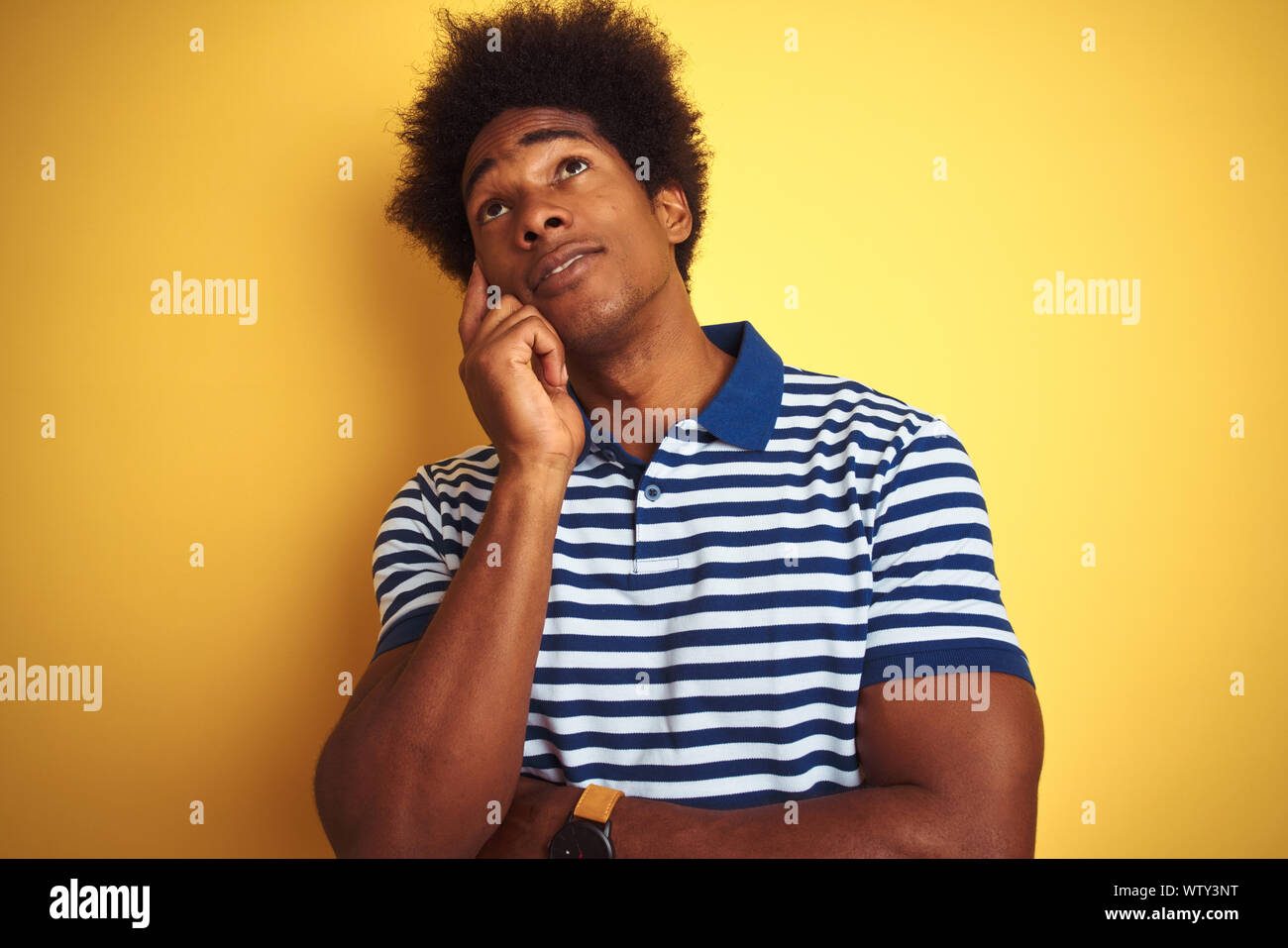 American man with afro hair wearing navy striped polo standing over ...