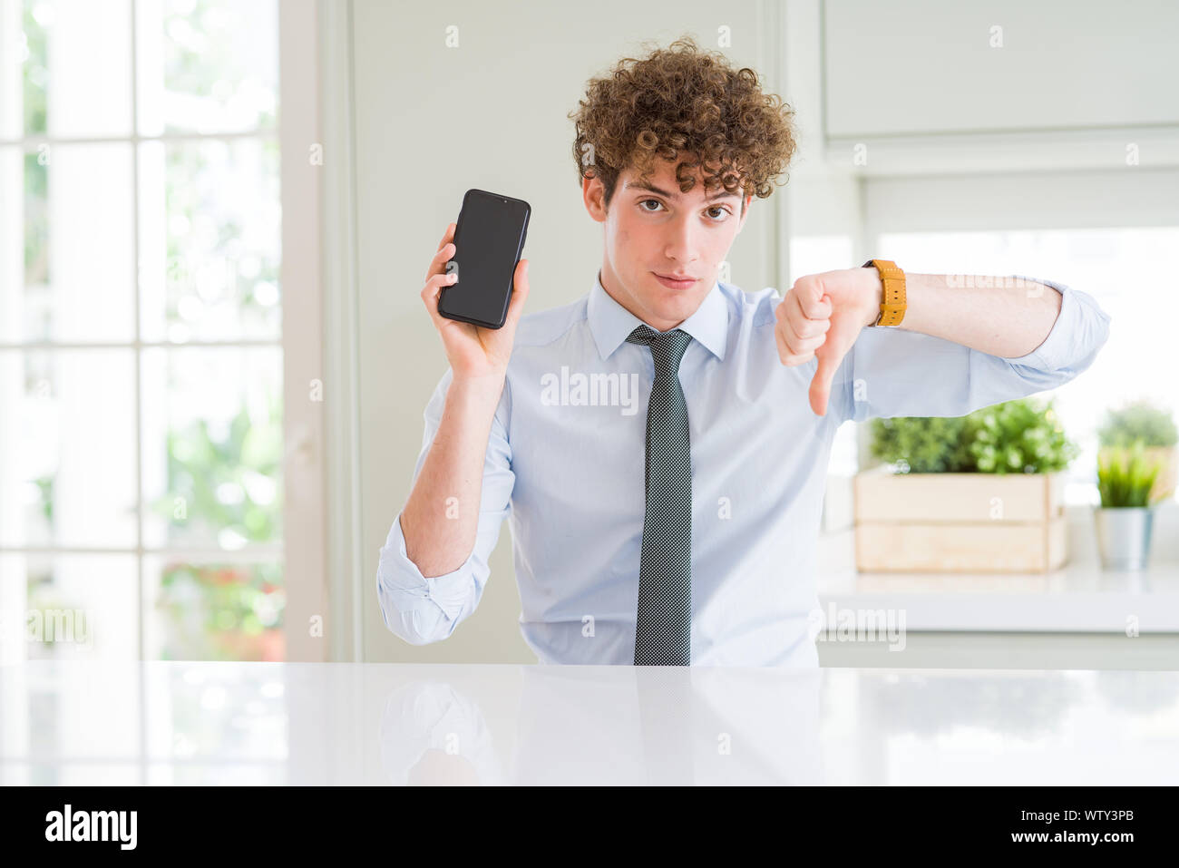 Young business man showing smartphone screen at the office with angry ...