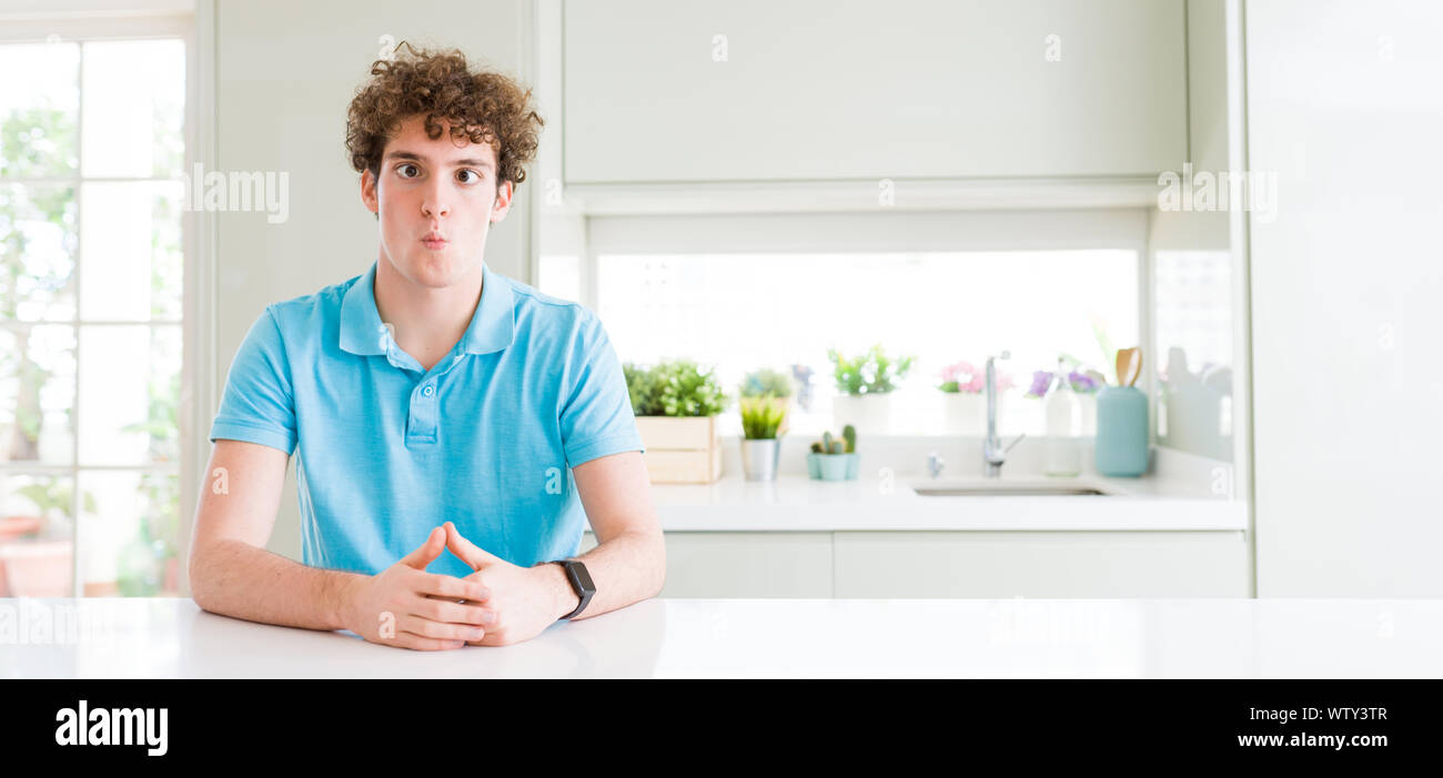 Wide shot of young handsome man at home making fish face with lips ...