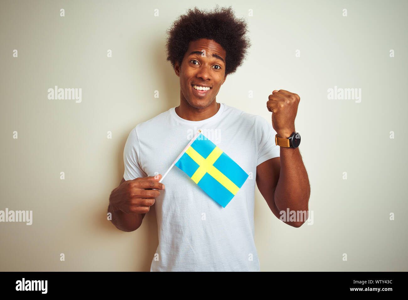 Young afro american man holding Sweden Swedish flag standing over ...