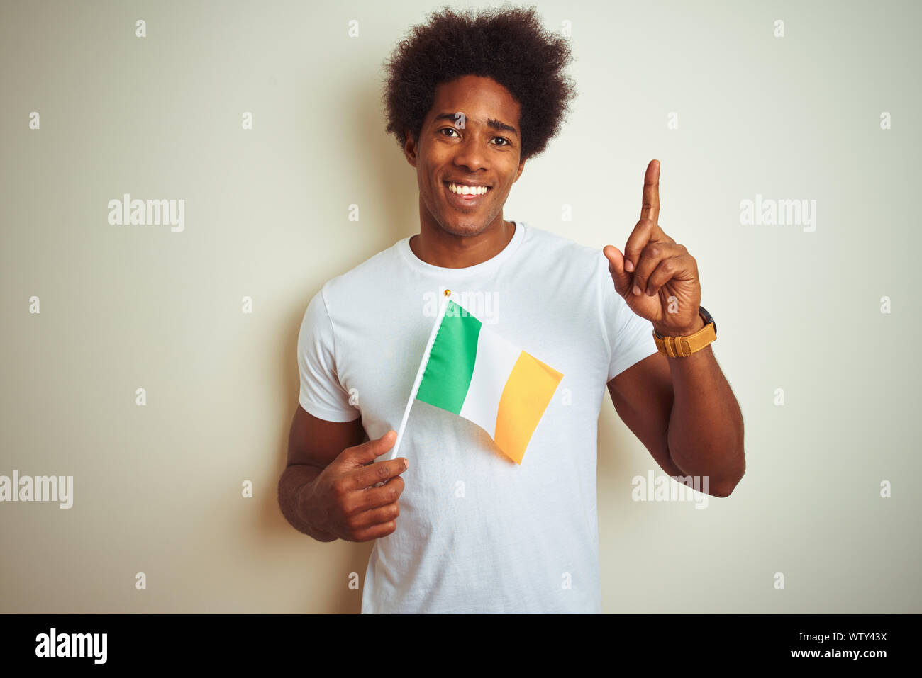 Young african american man holding Ireland Irish flag standing over ...