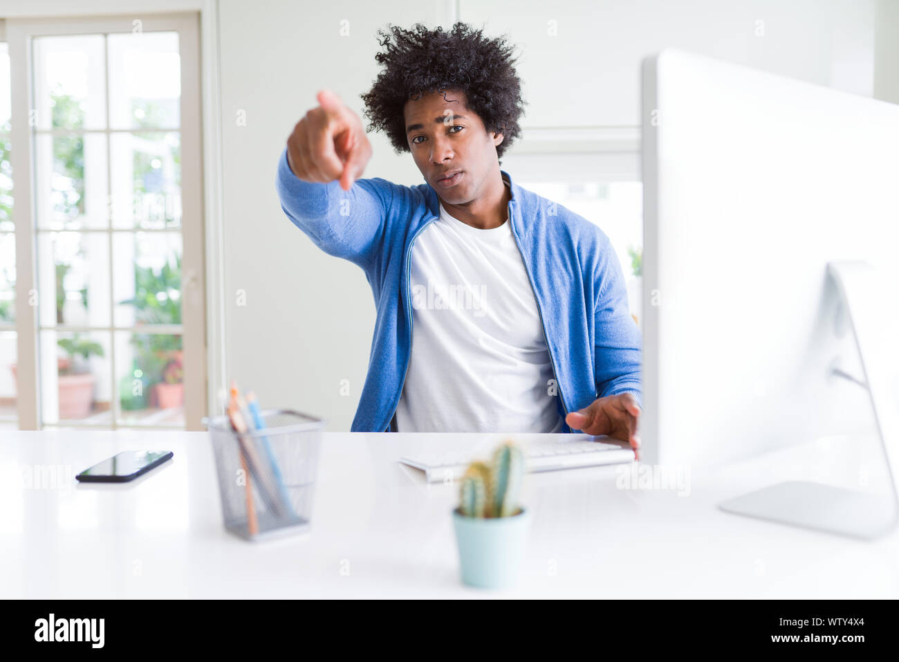 African American man working using computer pointing with finger to the ...
