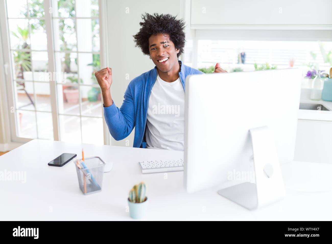 African American man working using computer celebrating surprised and ...