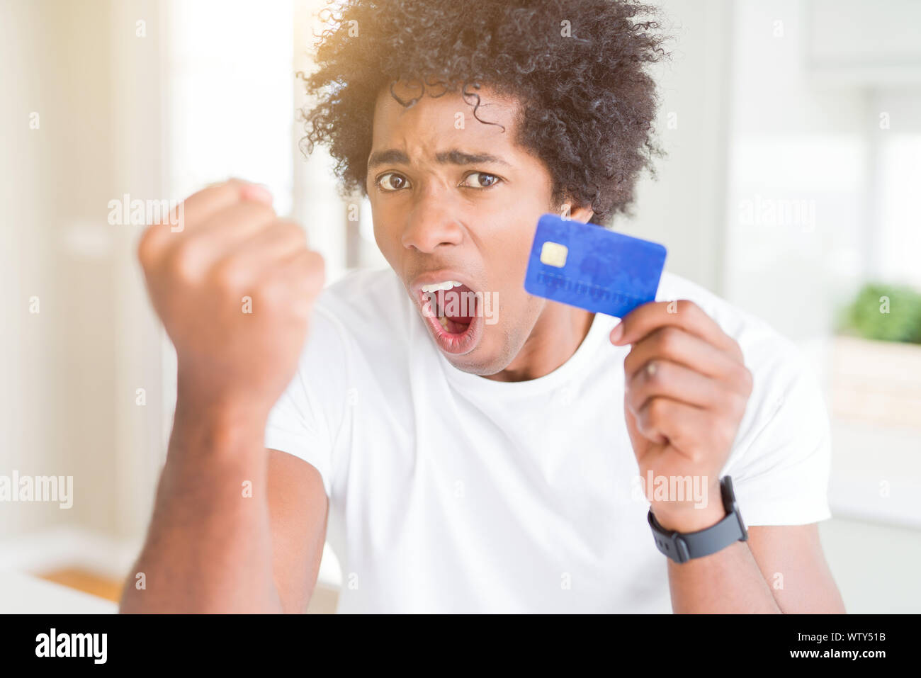 African American man holding credit card annoyed and frustrated ...