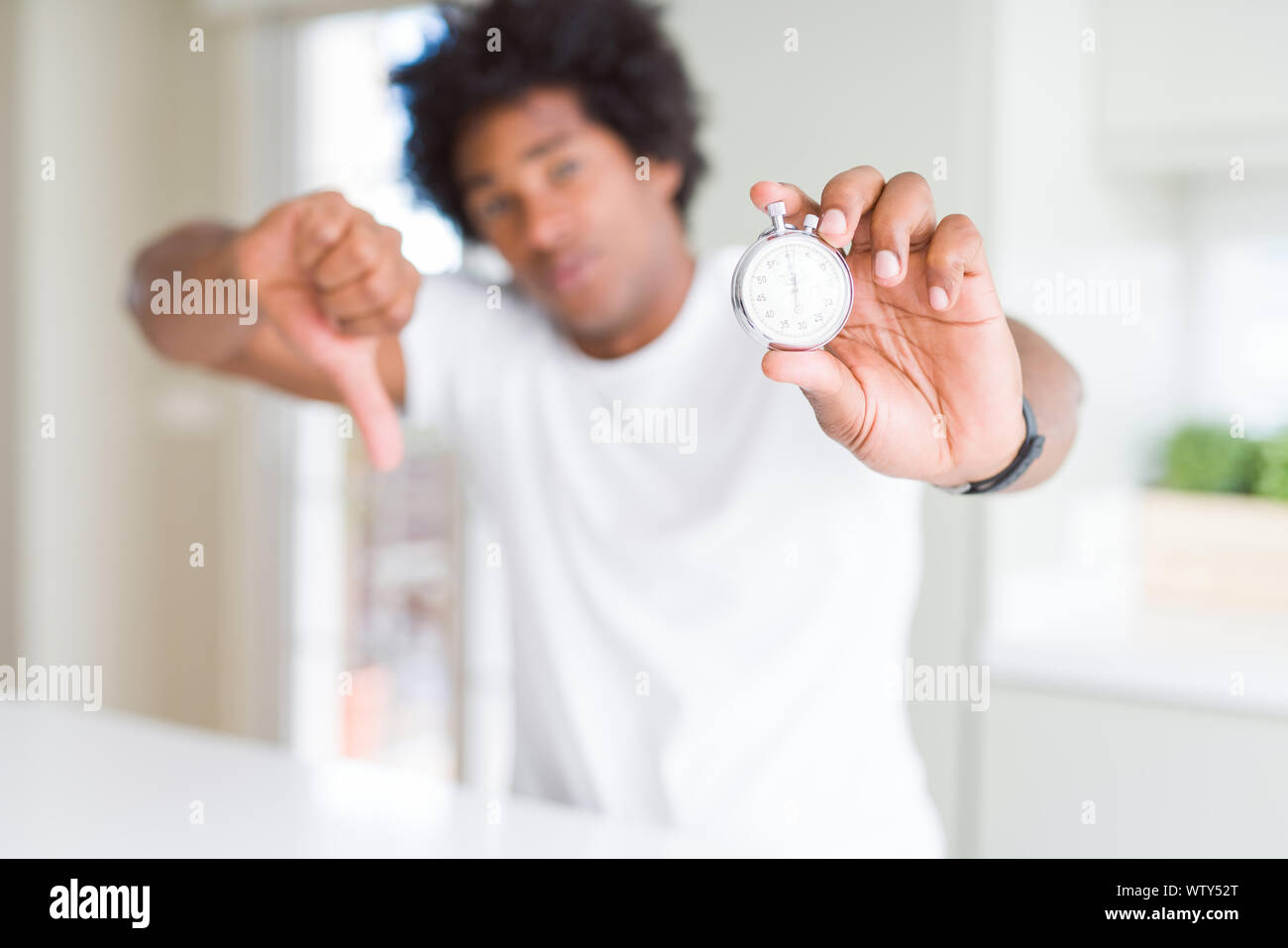 African American man holding stopwatch with angry face, negative sign ...