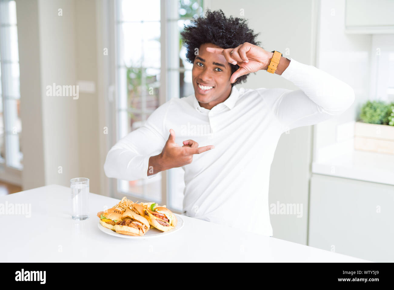 African American hungry man eating hamburger for lunch smiling making ...