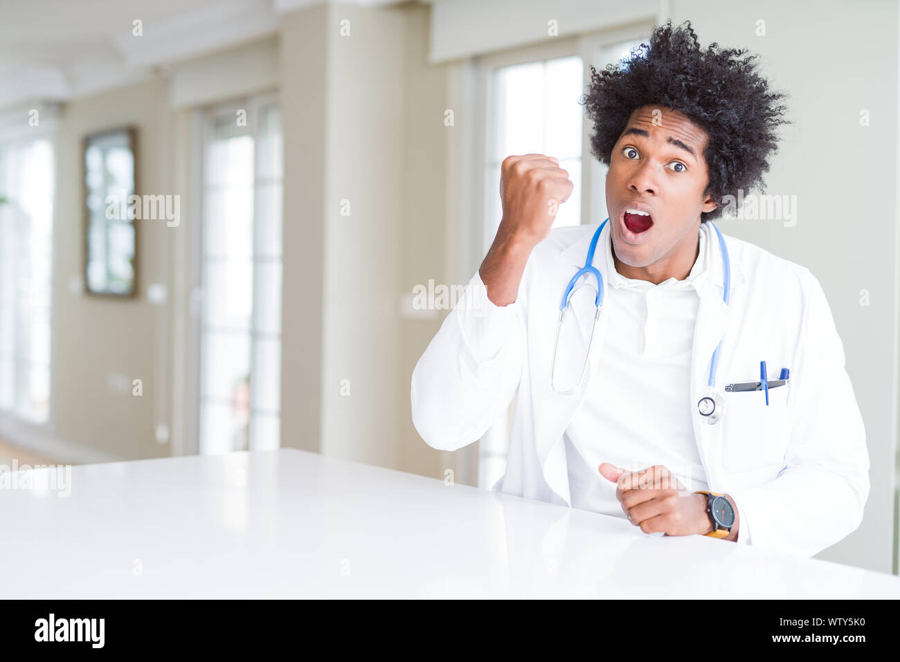 African American doctor man at the clinic angry and mad raising fist ...