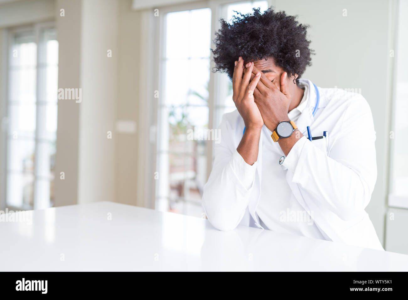 African American doctor man at the clinic with sad expression covering ...