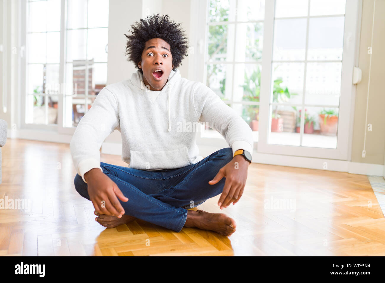 African American man sitting on the floor at home afraid and shocked ...