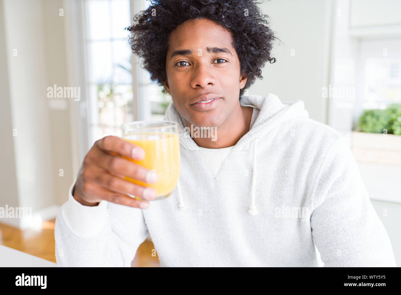 African American man holding and drinking glass of orange juice with a ...