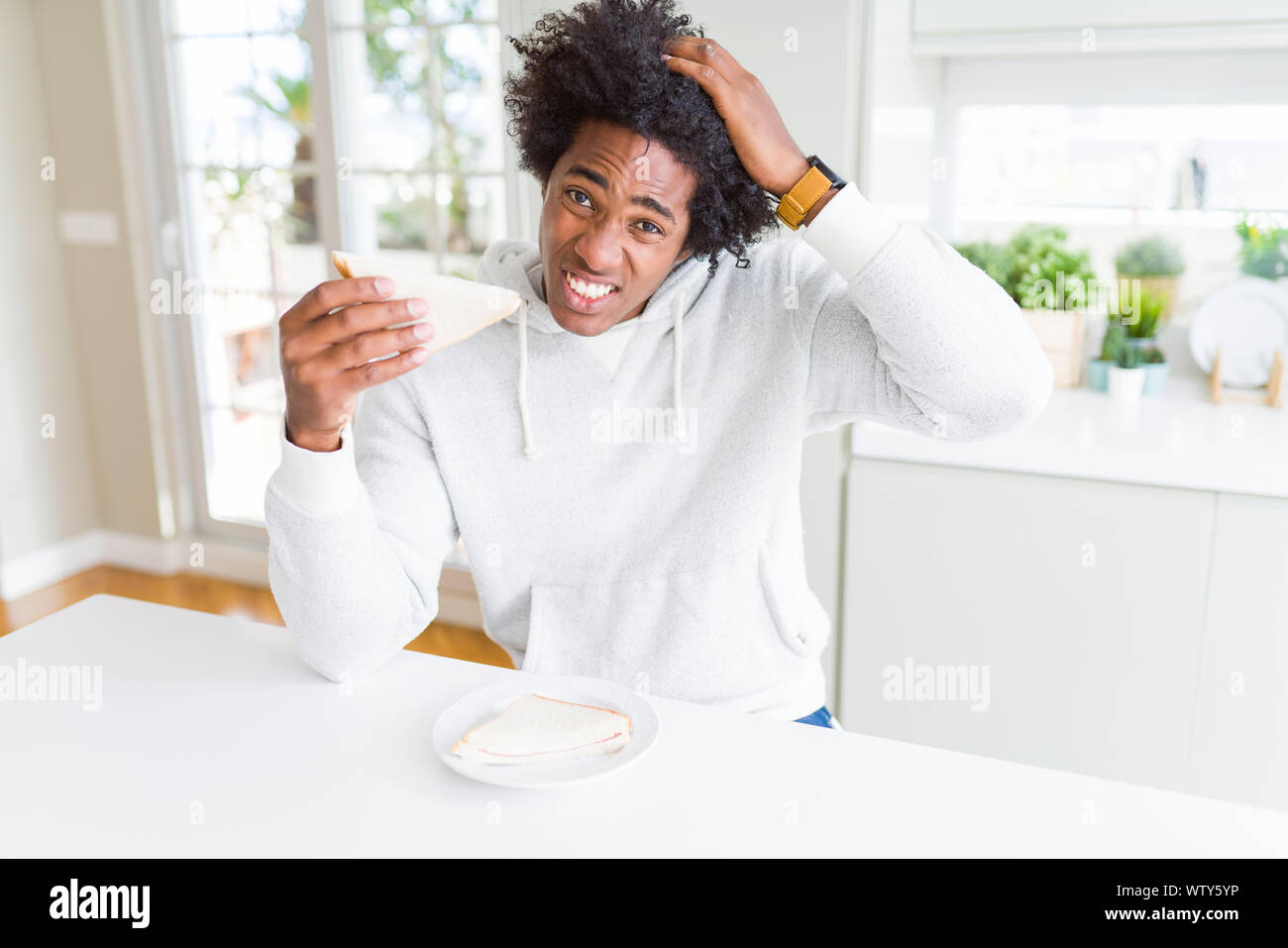African American man eating handmade sandwich at home stressed with ...