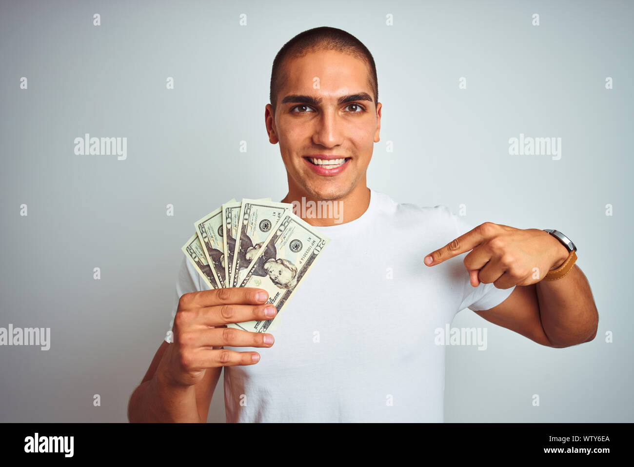 Young handsome man holding dollars over white isolated background with ...