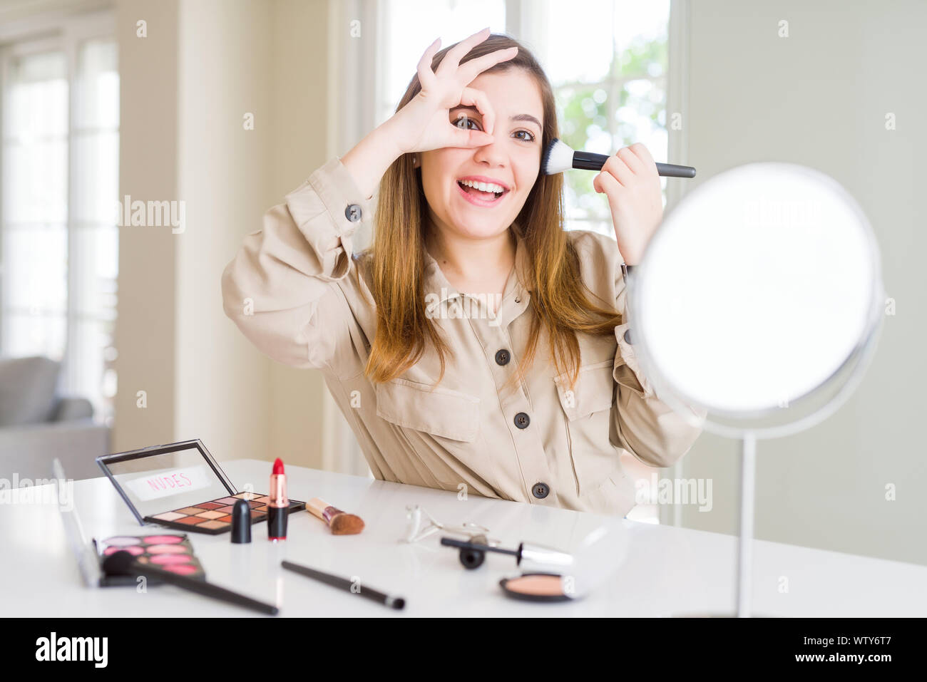 Beautiful young woman using make up cosmetics applying color using ...