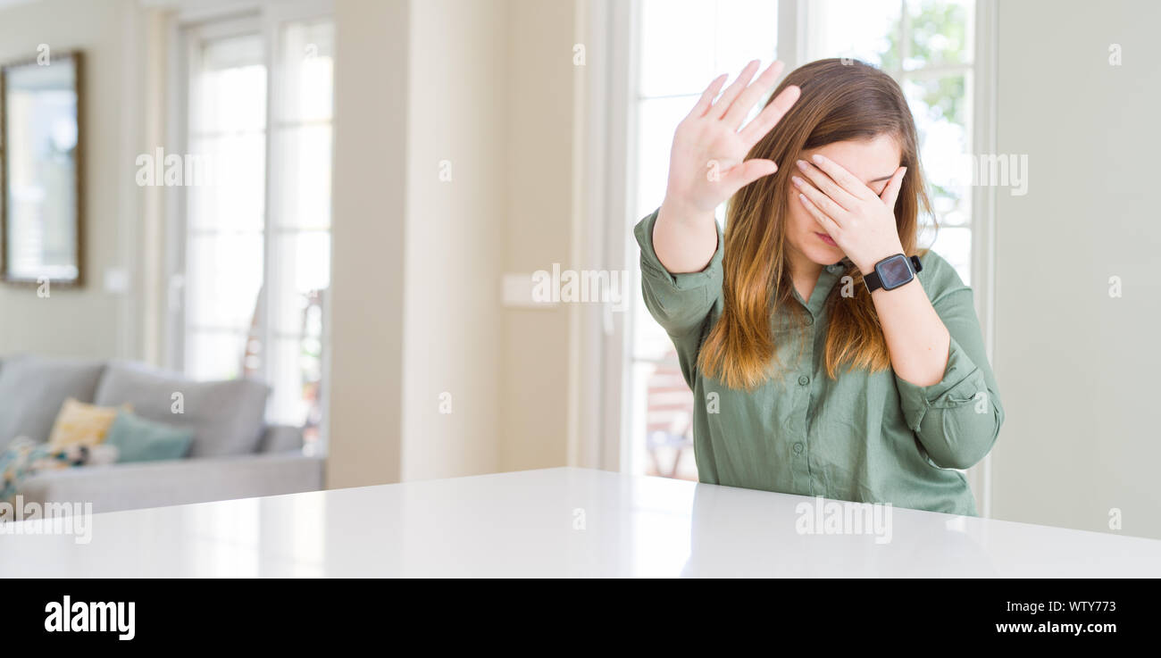 Beautiful young woman at home covering eyes with hands and doing stop ...